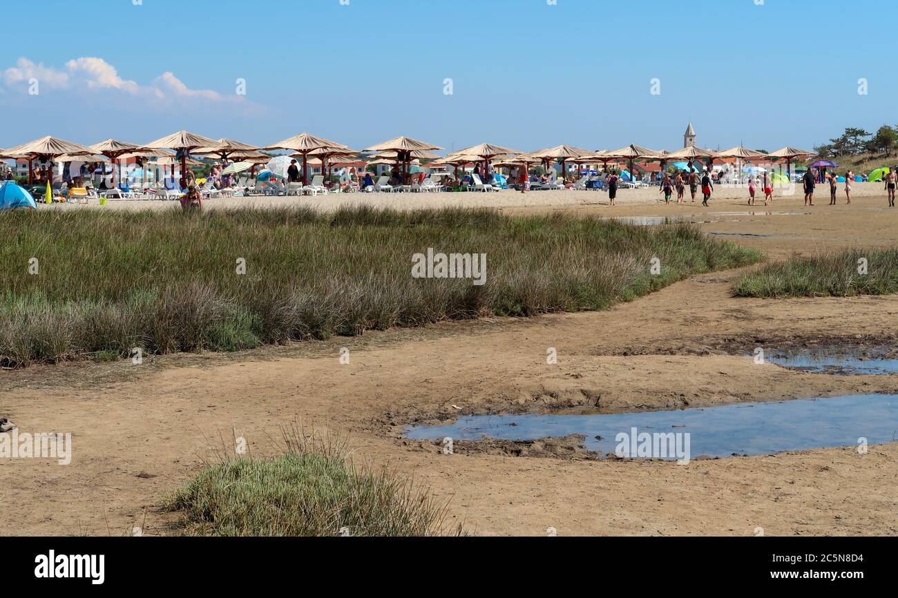 Sun parasols on Queen's beach viewed from Nin's mud lagoon Stock Photo ...