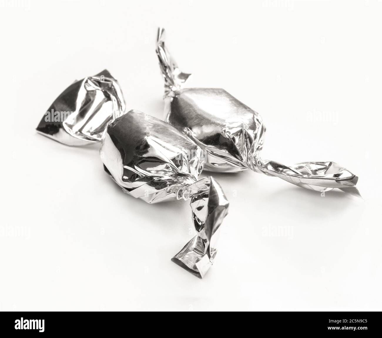 Two candies in grey shiny wrapping foil isolated on white background ...