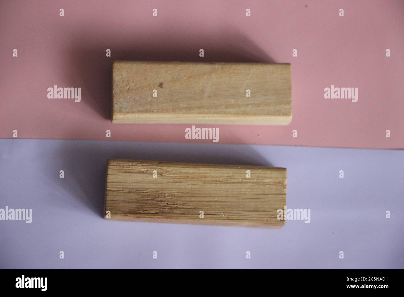 Two wood blocks forming equal sign on soft pink and lilac background ...