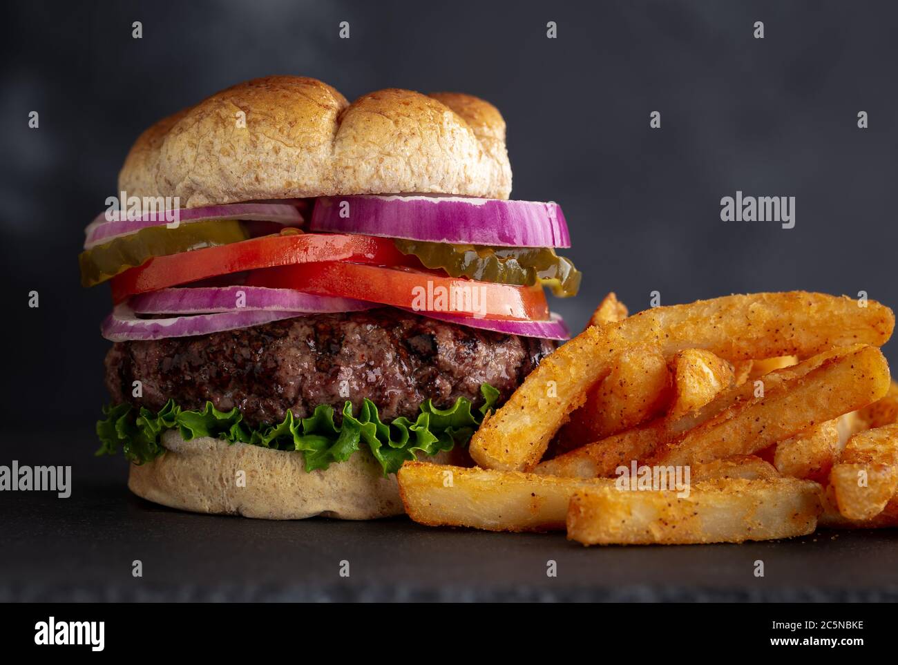 Juicy grilled hamberger with lettuce, tomato, pickle and onions on ...