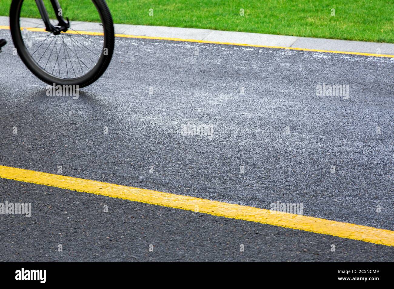 asphalt bicycle path wet after rain with yellow markings with a passing ...