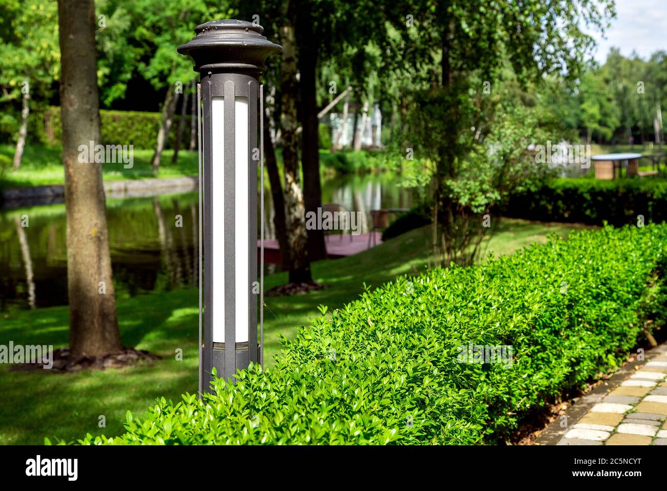 Iron ground lantern in the park mounted in deciduous bushes in the ...