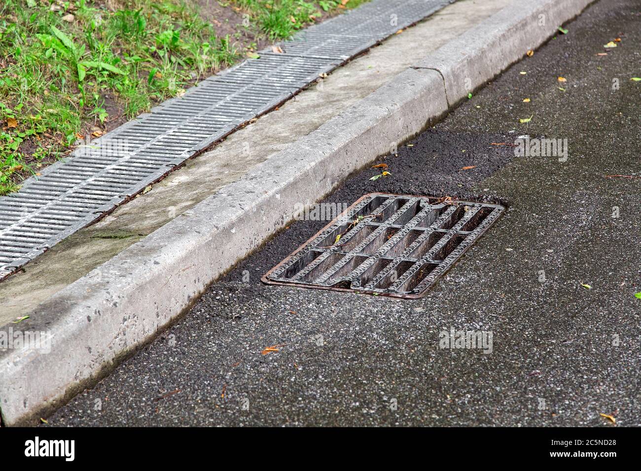 storm systems on an asphalt road a manhole grille behind a curb a ...
