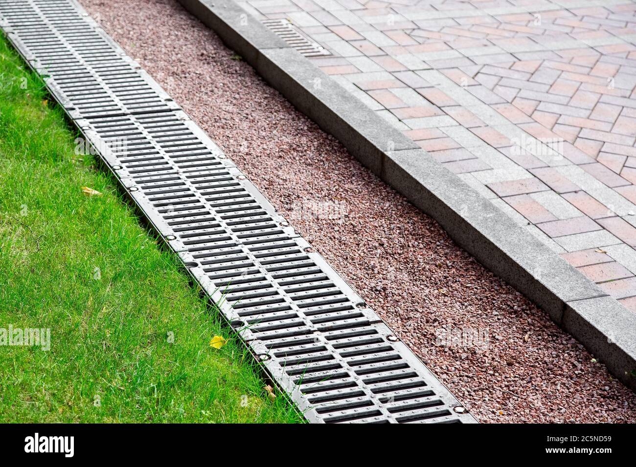 drainage system in the park between green grass and stone pavement ...