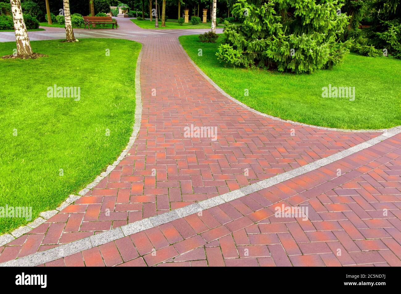 crossing a pedestrian footpath of red tile in a park with green spaces ...