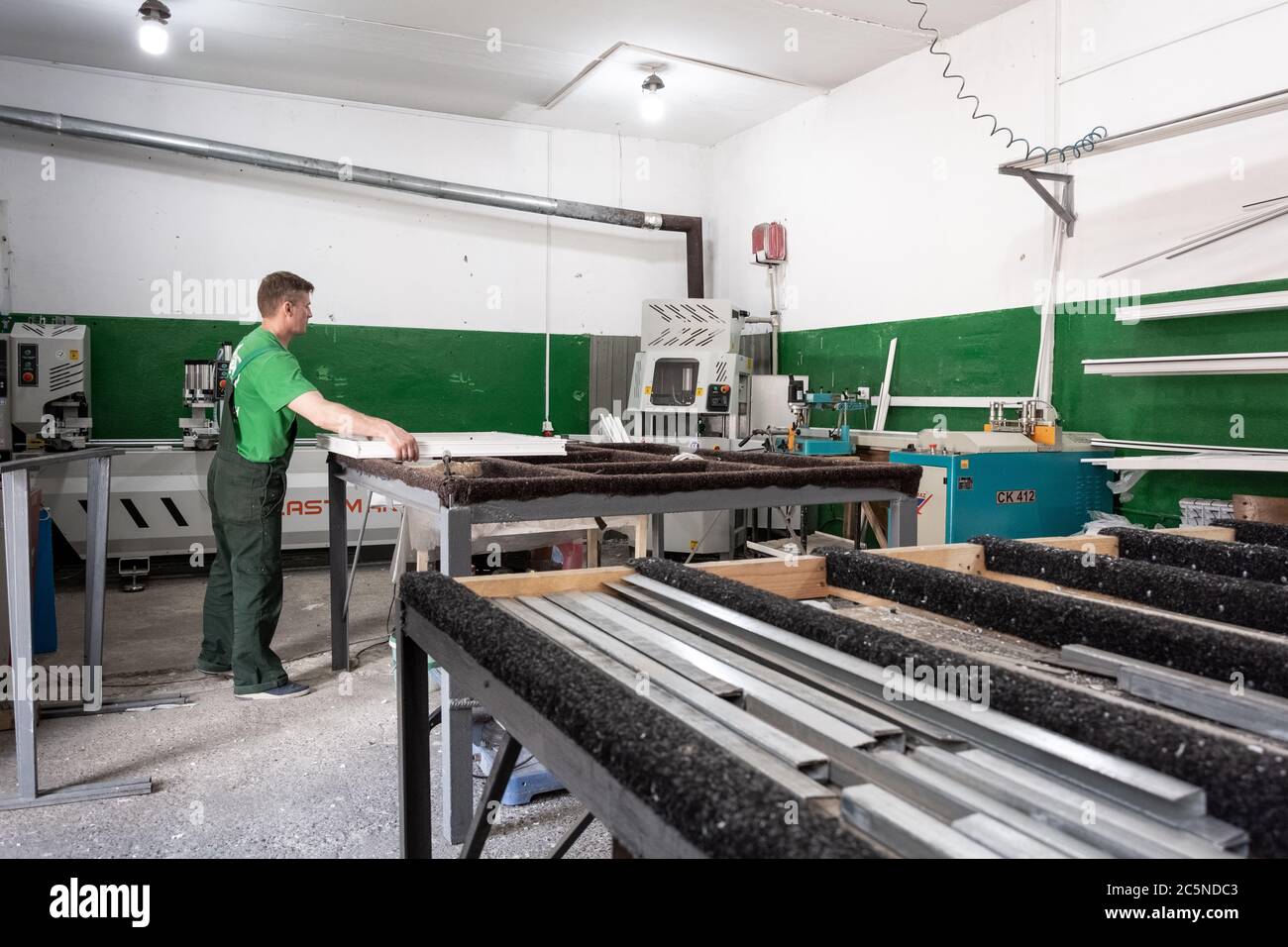 Worker on a machine for welding windows and doors made of PVC. Factory ...