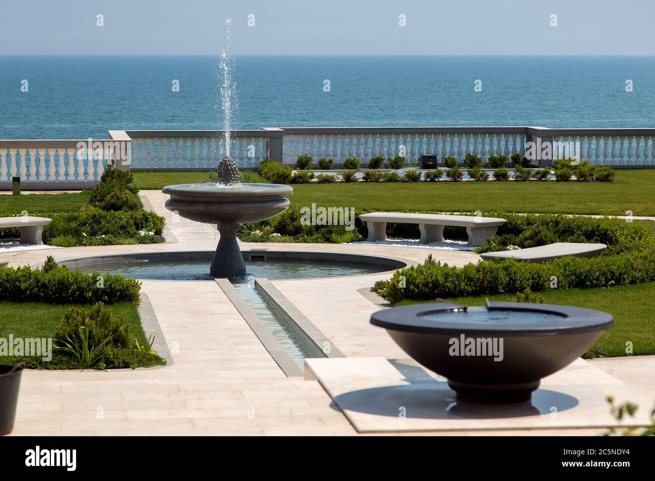 the backyard of a landscaped mansion with a stone fountain and stream ...