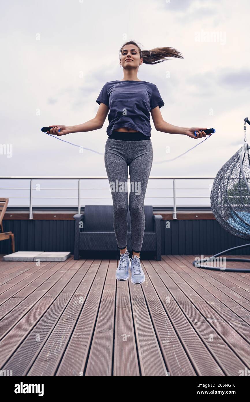 Sporty young woman jumping over skipping rope Stock Photo - Alamy