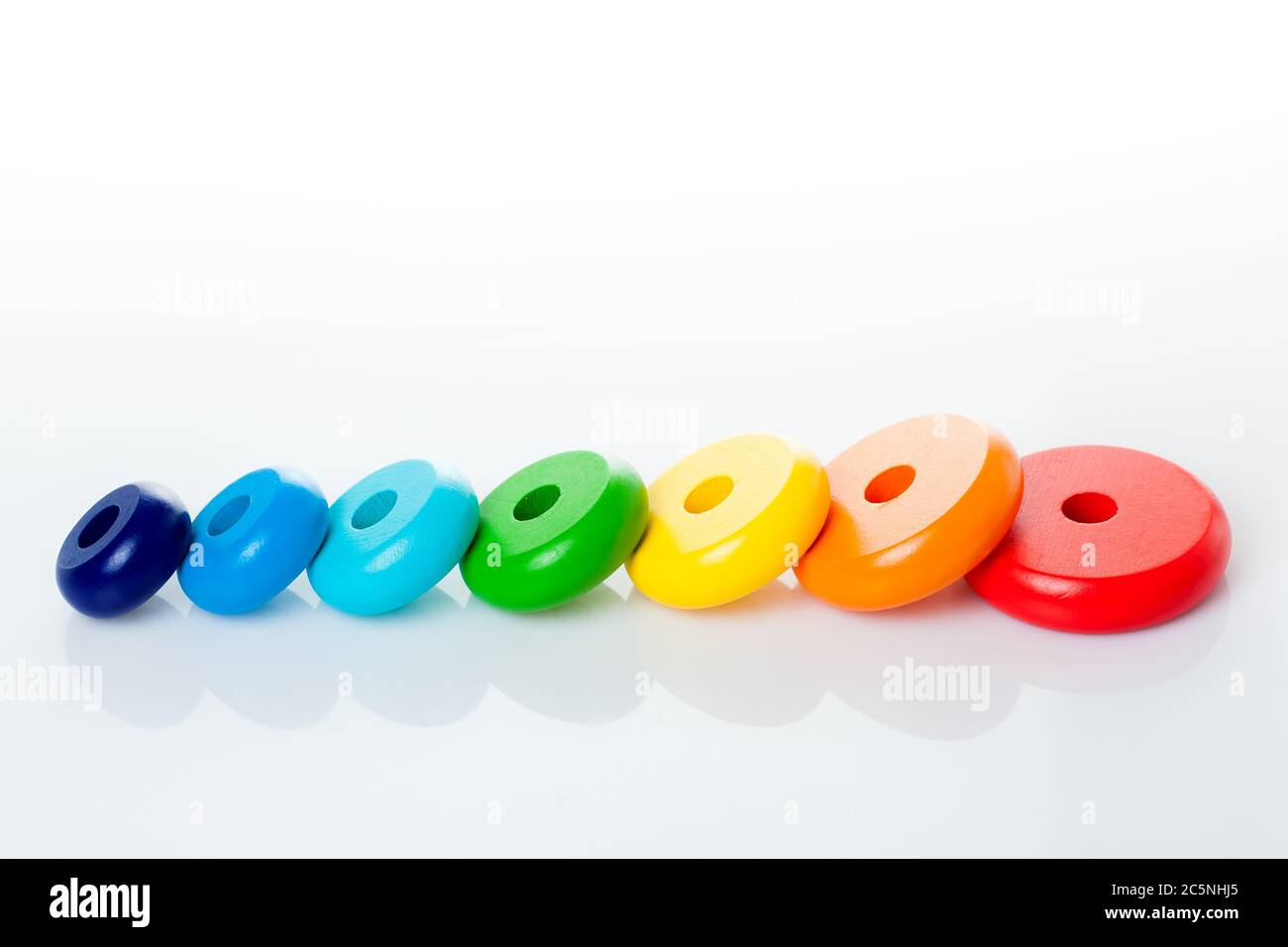 children pyramid of wooden round rings of multi colors lies on a white ...