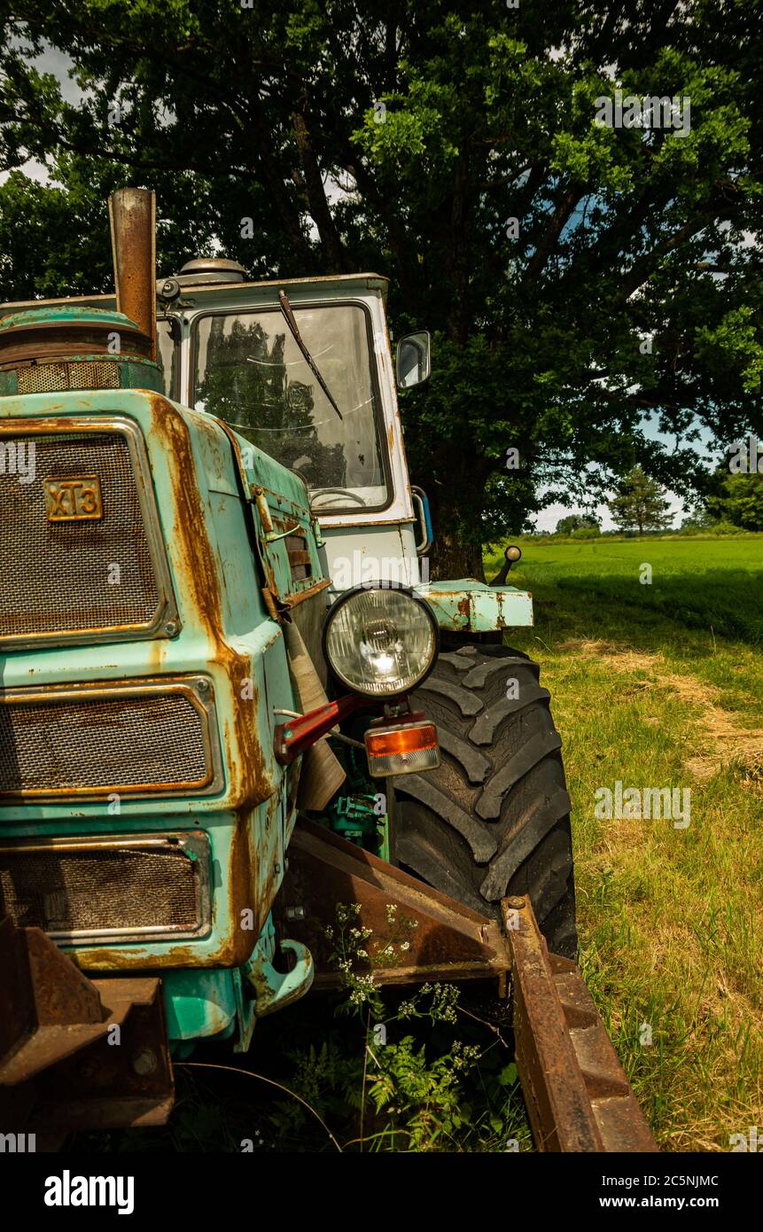 Old Russian tractor with a lamp and tire, green grass Stock Photo - Alamy
