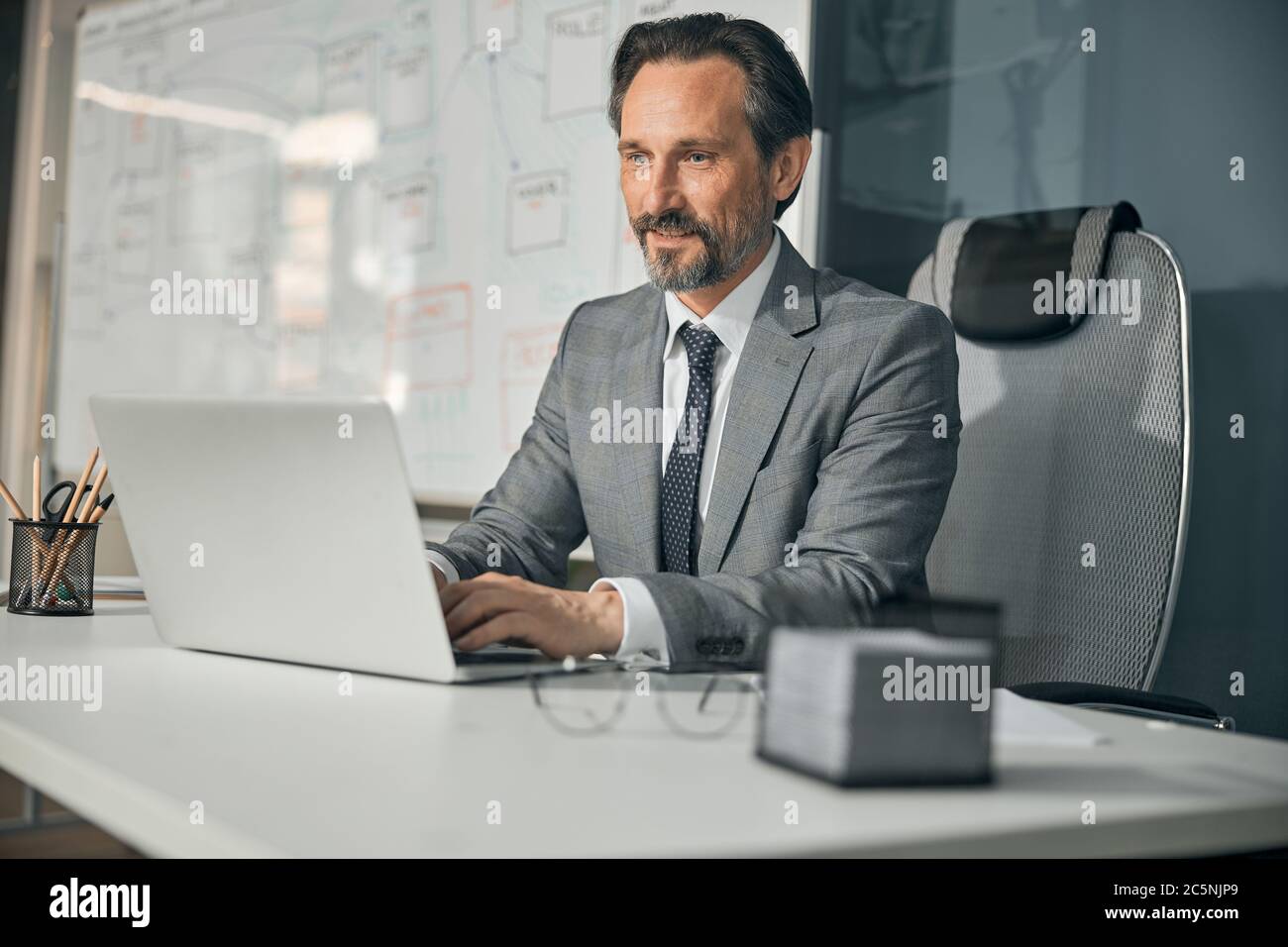 European businessman wearing grey coat sitting on the office chair ...