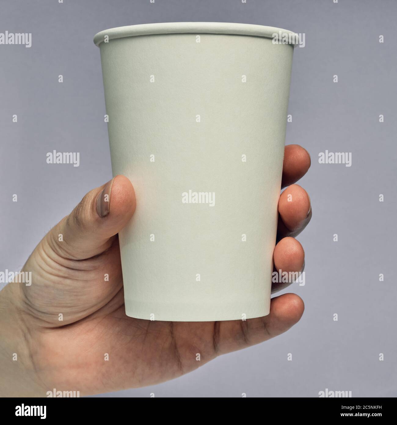 Paper cup in hand on a colored background. Eco-friendly materials in a ...