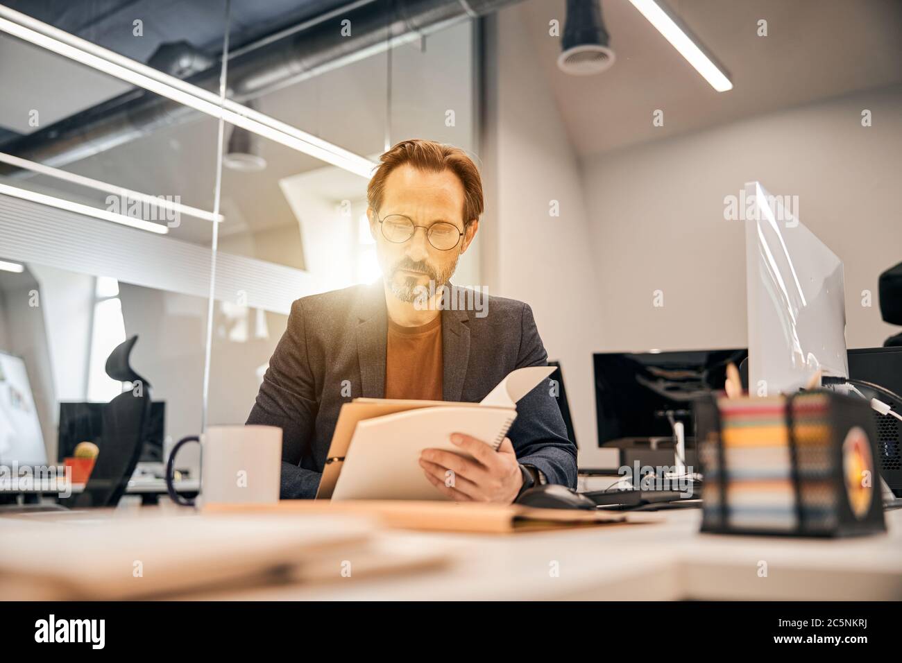 Executive businessman posing with clipboard in office interior Stock ...