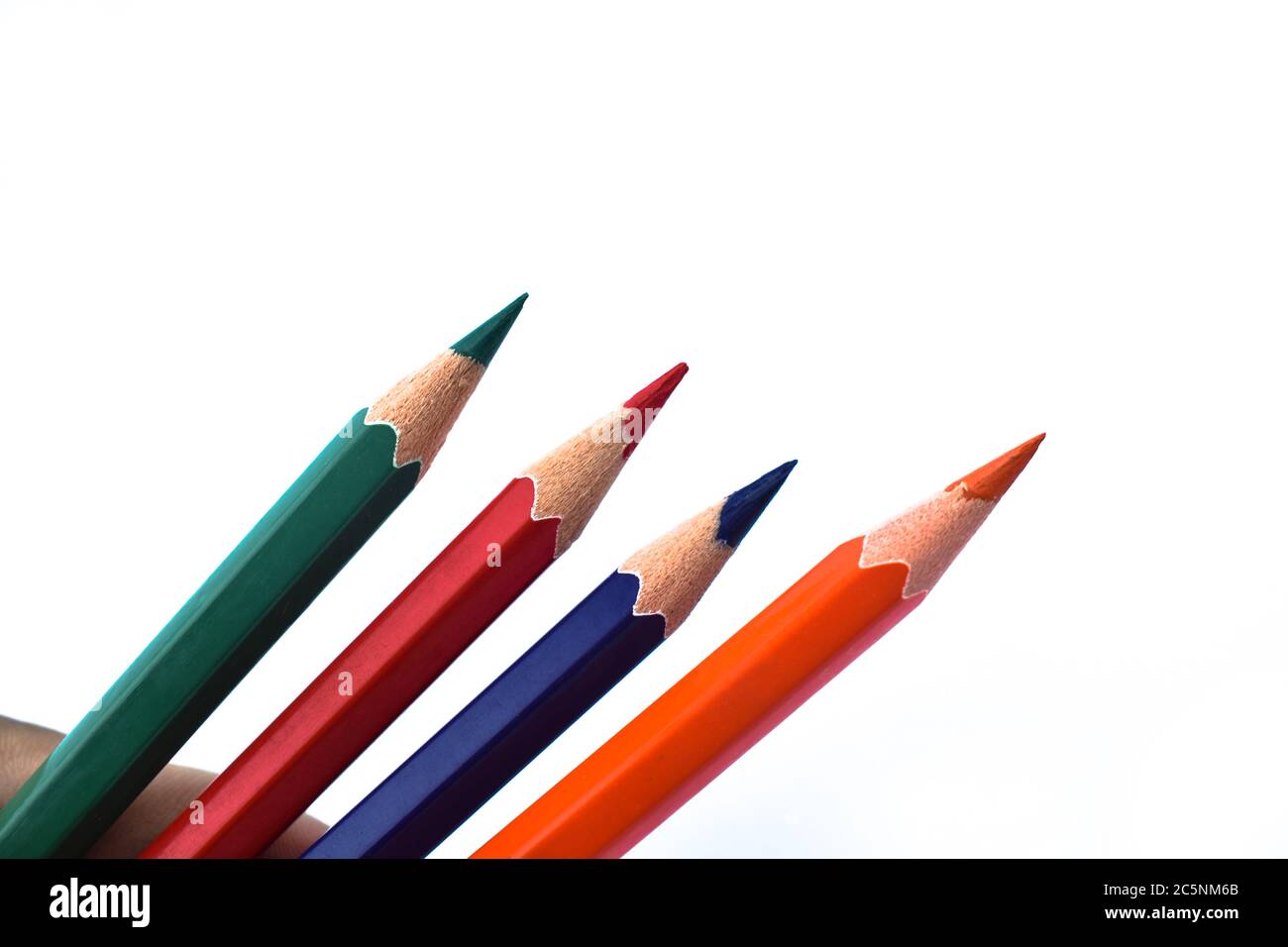 Four different colored wood pencil crayons scattered on a white paper ...