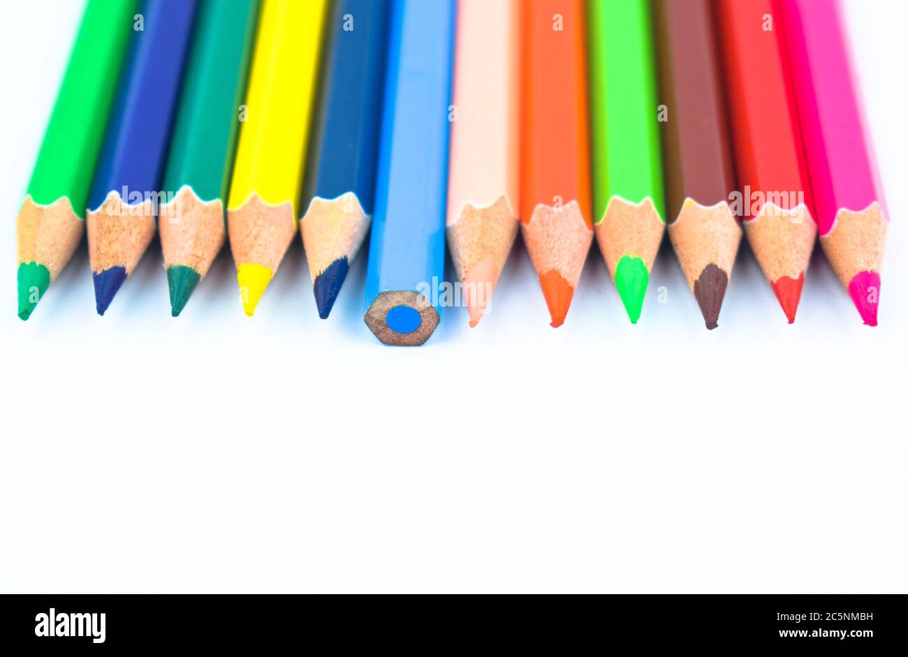 One line of different colored wood pencil crayons placed on an empty ...