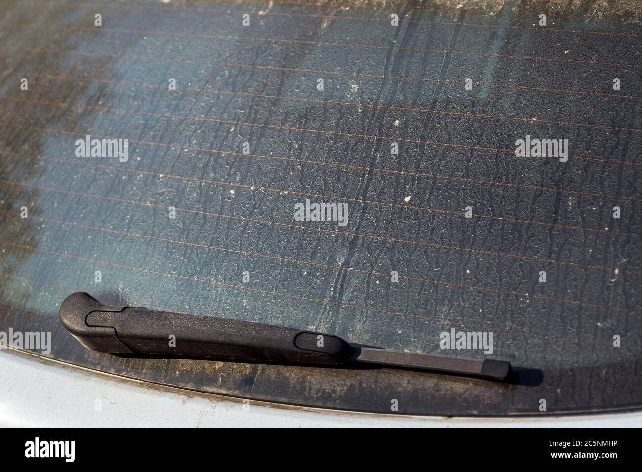 Close-up of the rear window and wiper of a dirty car, part of a car ...
