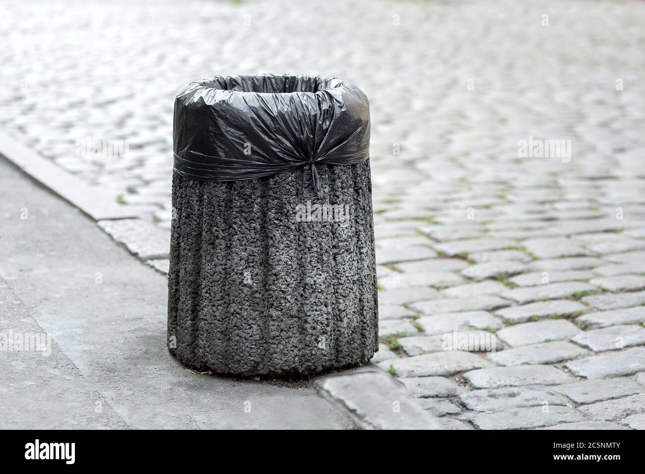 Stone garbage can with garbage bag on a pedestrian pavement of paving ...