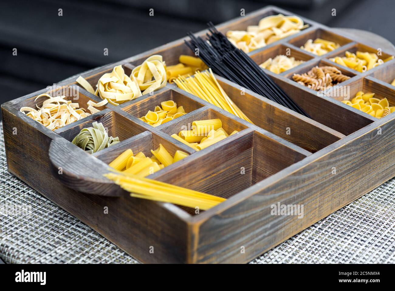 Wooden box with cells filled with traditional Italian food, pasta of ...