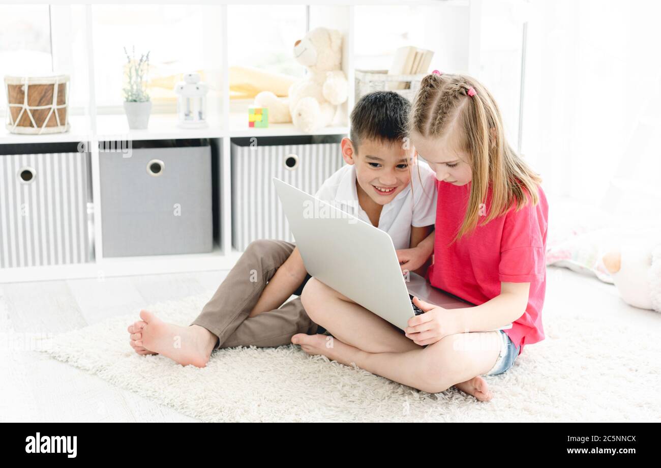 Cute little girl and boy using computer in bright kids room Stock Photo ...