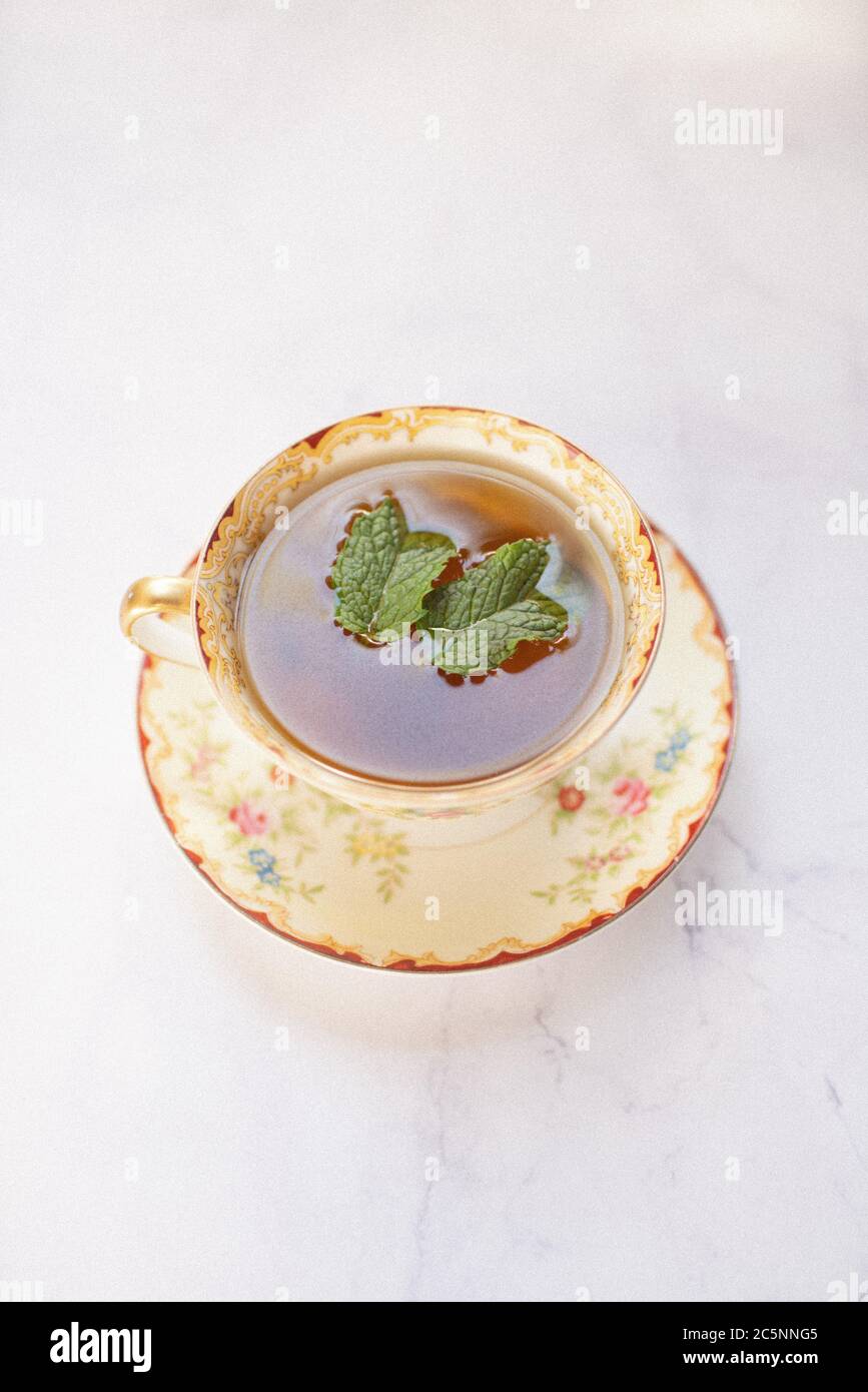 Traditional mint tea cup with fresh mint leaves on a white marble table ...