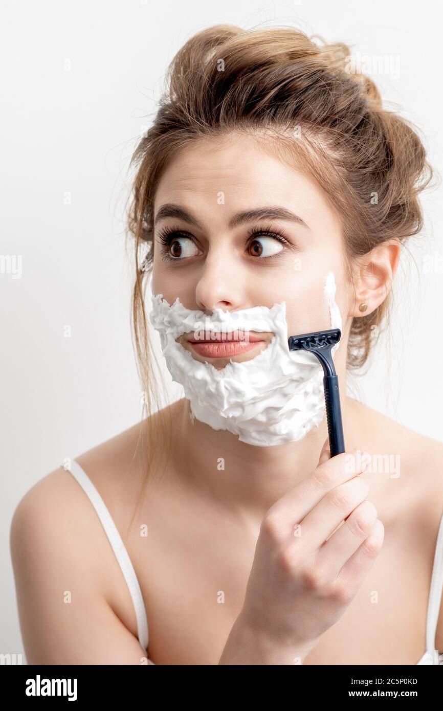 Beautiful young caucasian woman shaving her face by razor on white ...