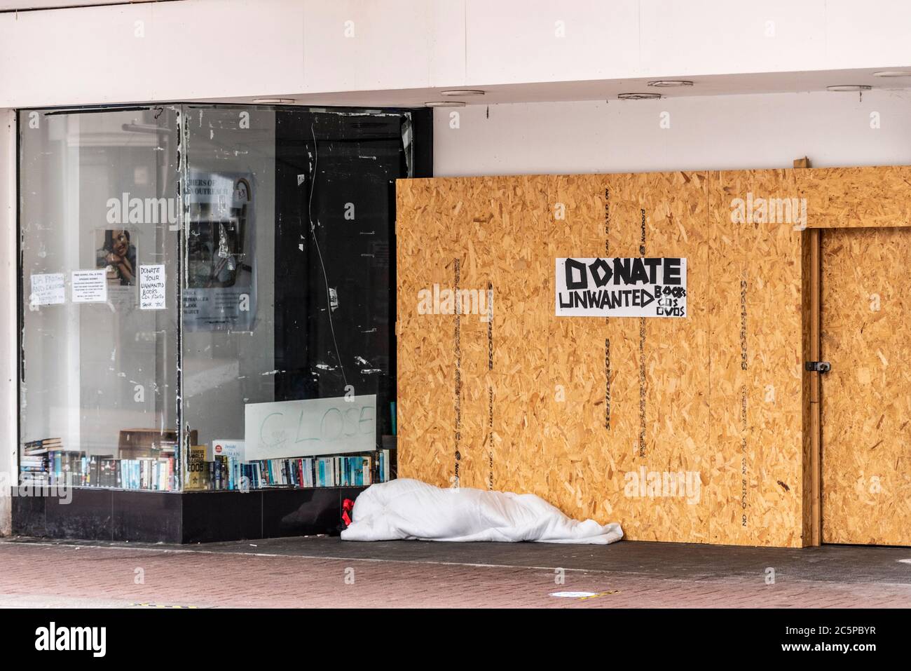 Homeless person rough sleeping in doorway of closed shop in High Street ...