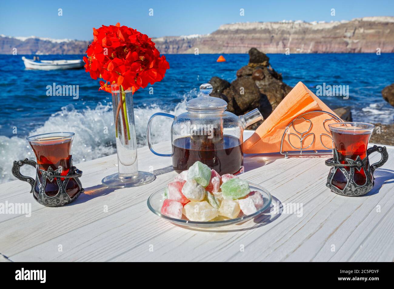 Tea and sweets on the beach against the background of the sea wave ...