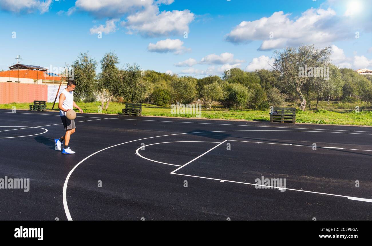 Man dribbling in a basketball court on a sunny day Stock Photo - Alamy