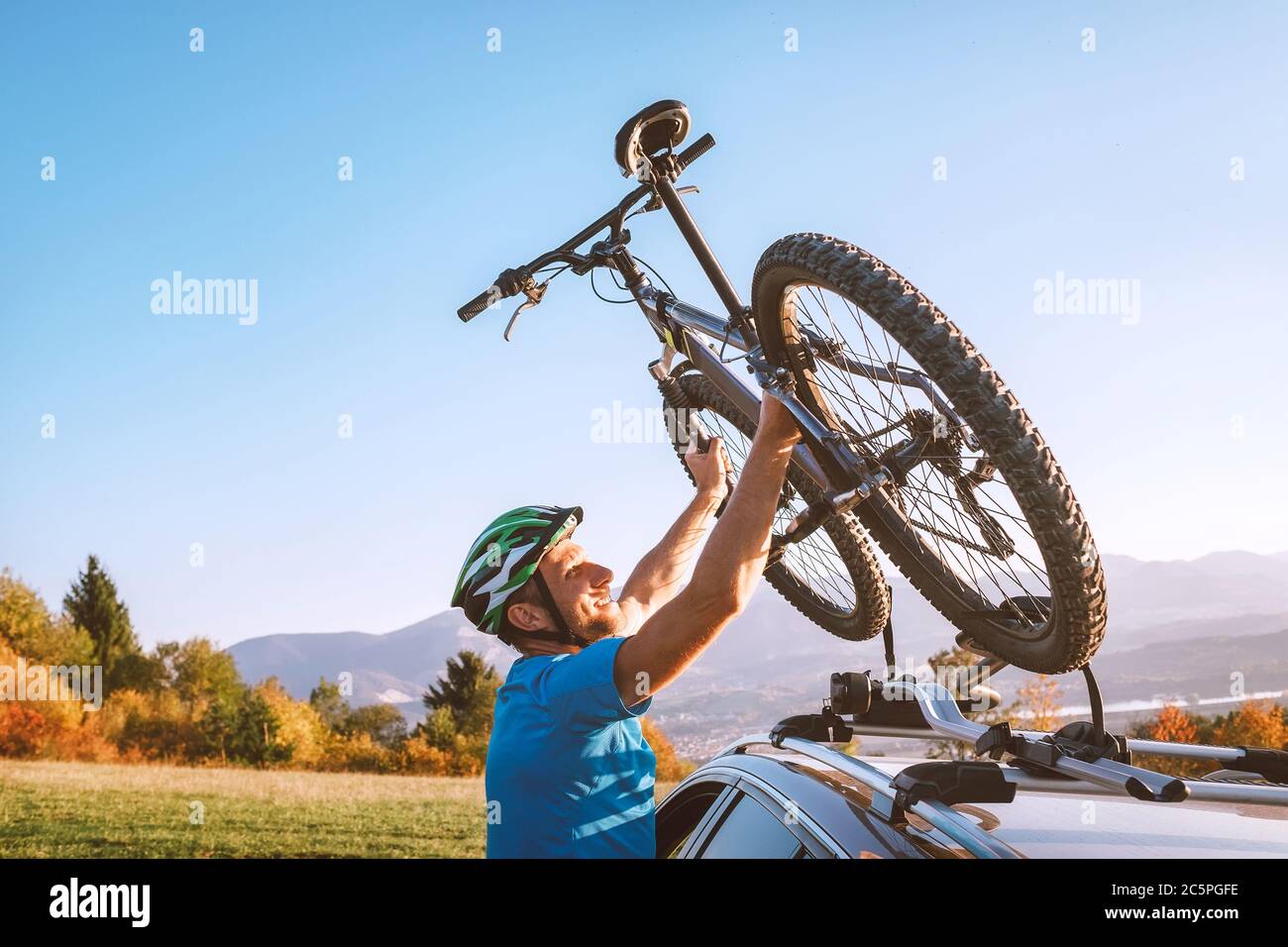 Mountain biker man take of his bike fronm the car roof. Active sport ...
