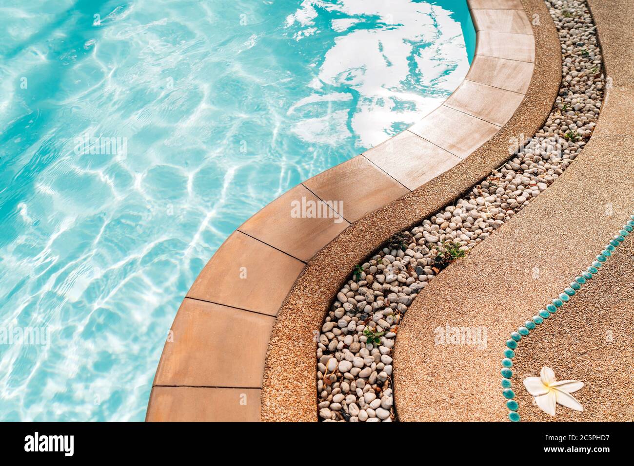 Curved swimming pool paved edge with pebbles. Clean transparent pool ...