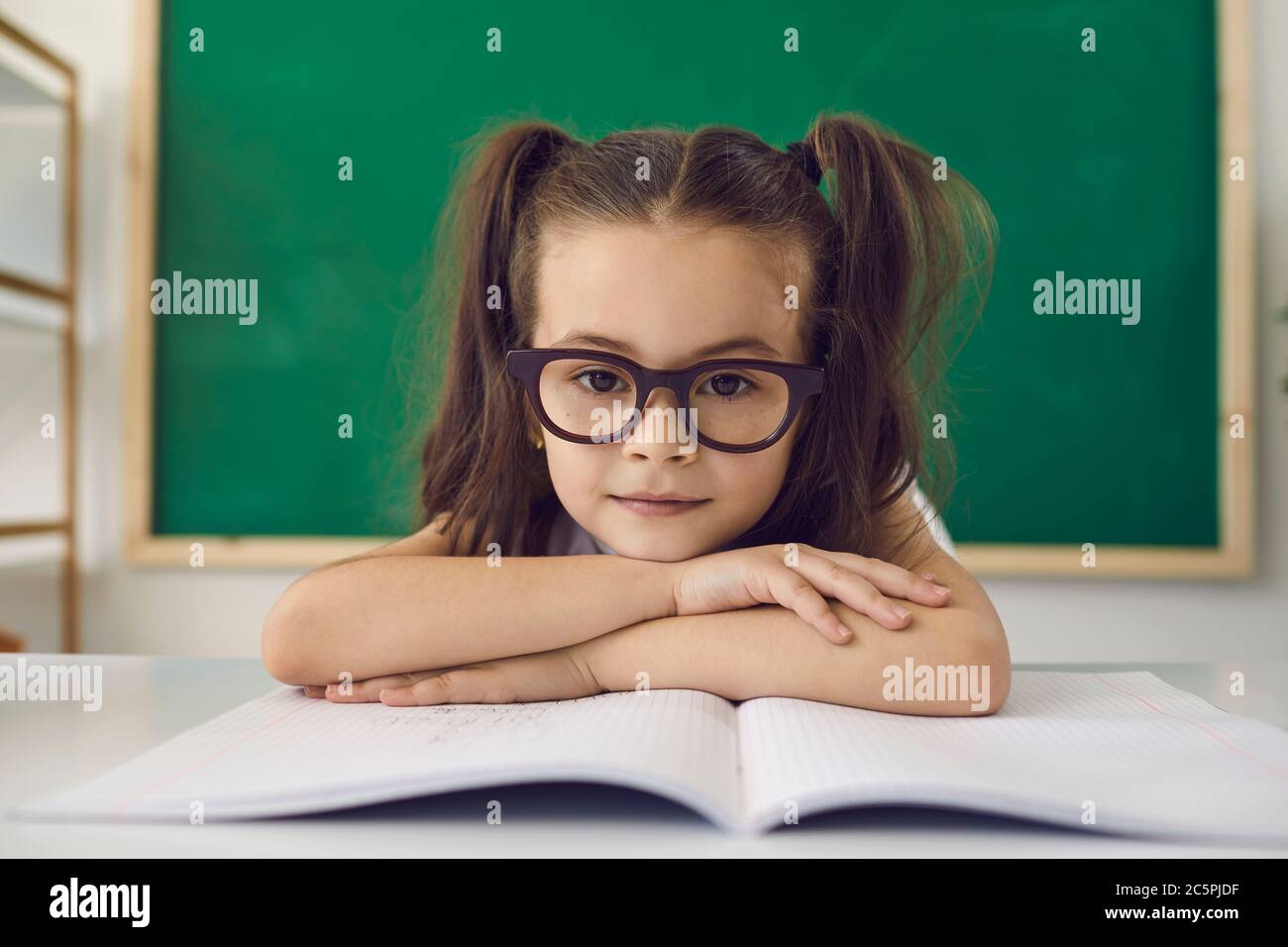 Back to school concept. Little smart girl in glasses with a book at the ...