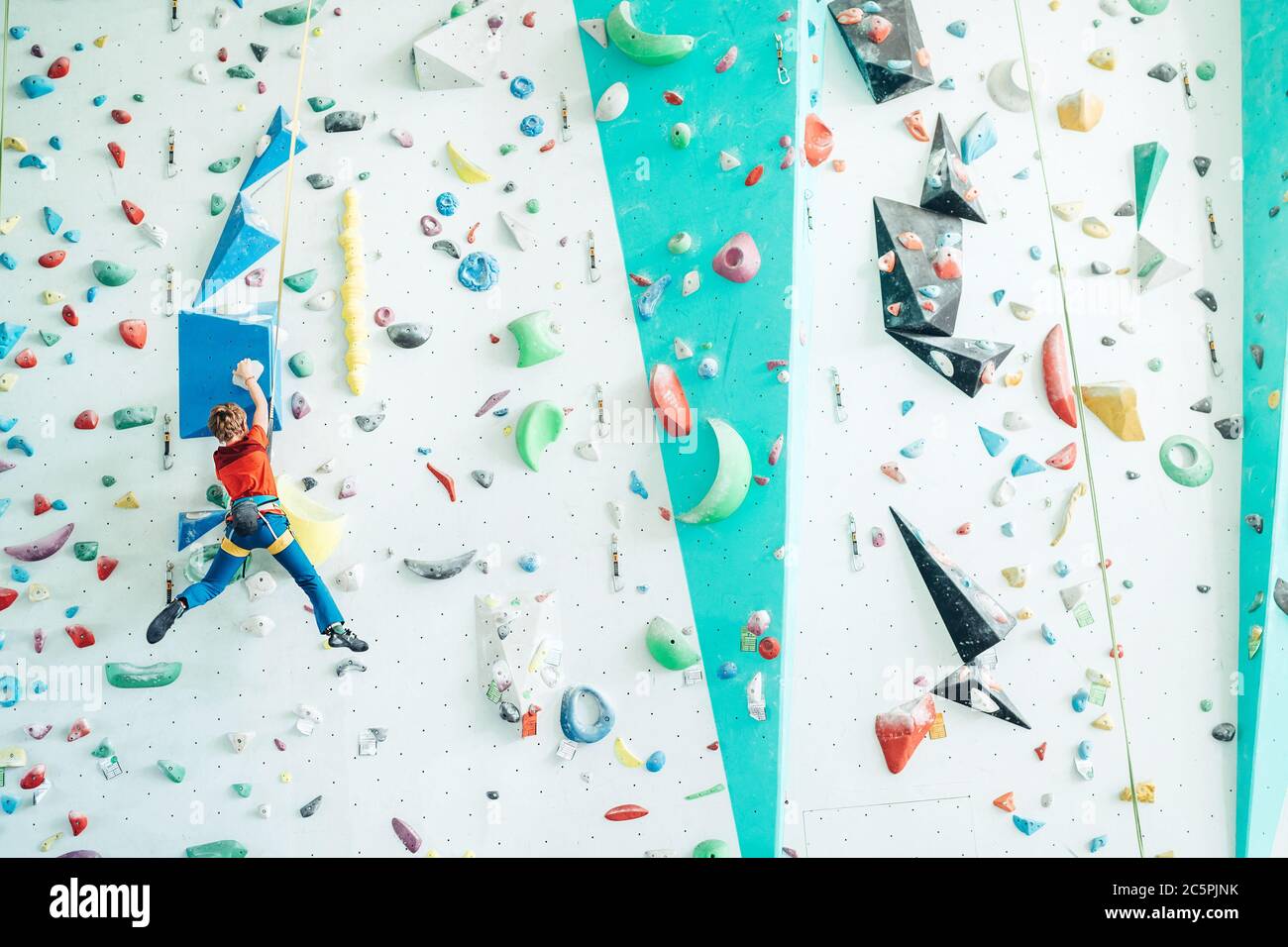 Teenager boy at indoor climbing wall hall. Boy is climbing using an ...