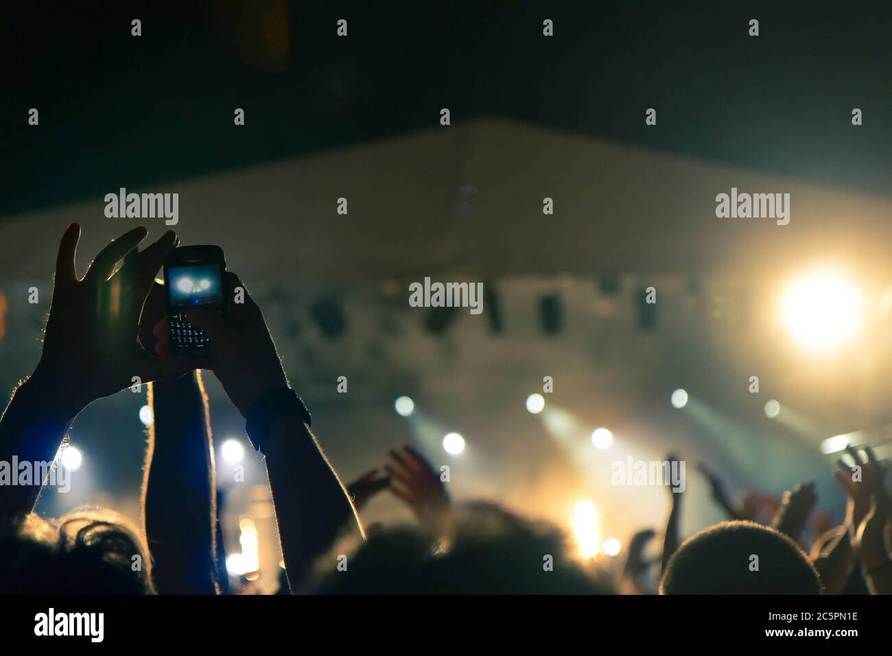 Concert crowd point of view in front of a lit stage for a night ...