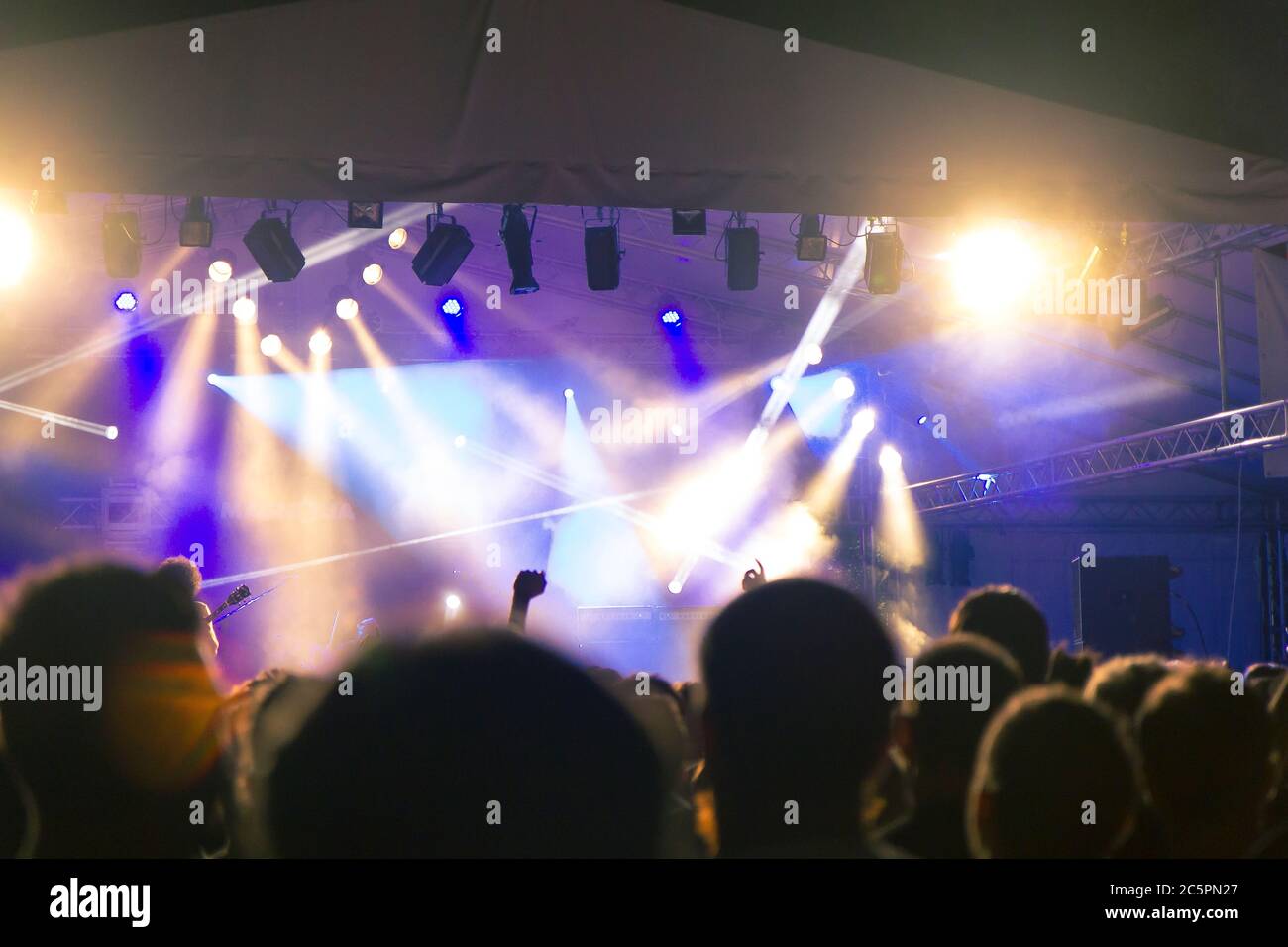 Concert crowd point of view in front of a lit stage for a night ...
