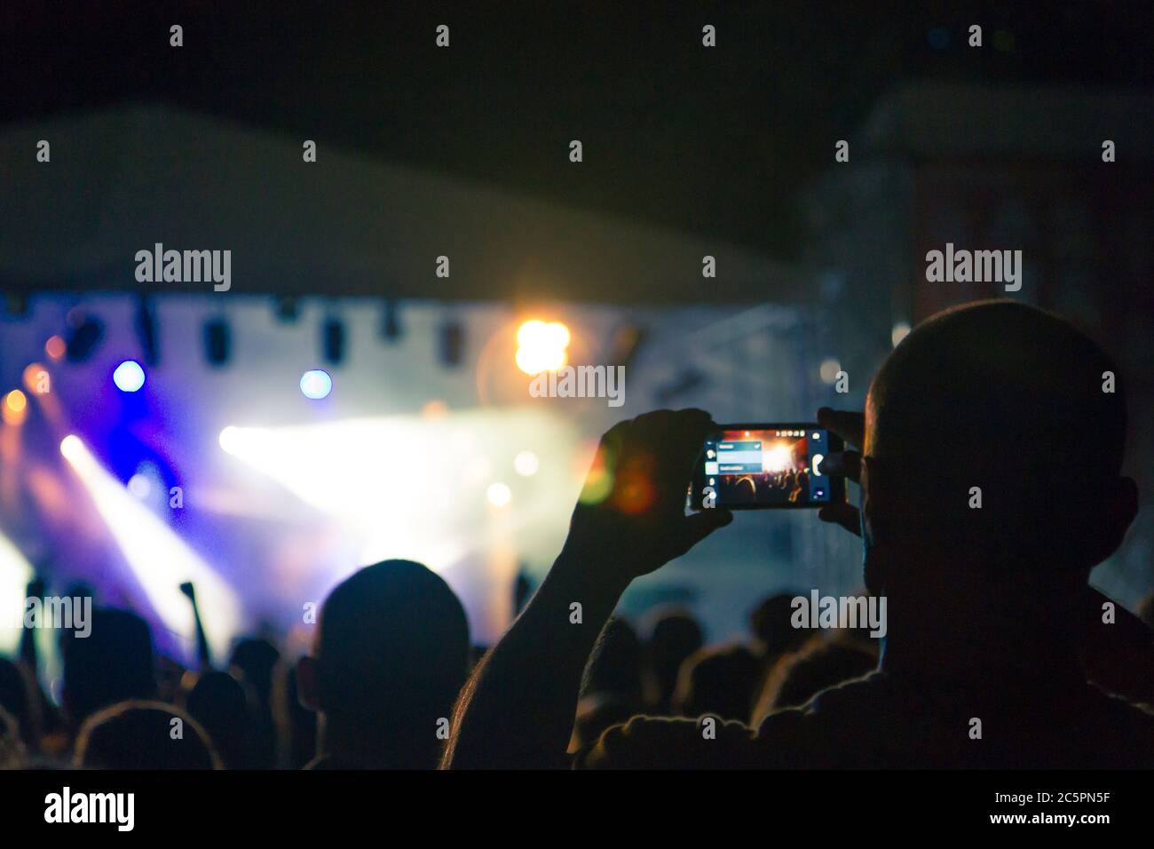 Concert crowd point of view in front of a lit stage for a night ...