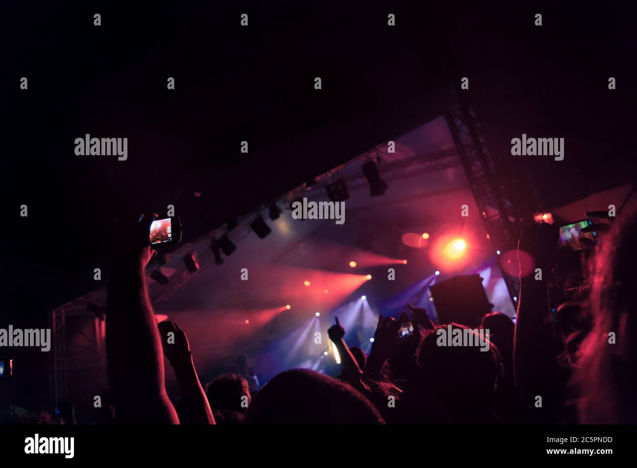 Concert crowd point of view in front of a lit stage for a night ...