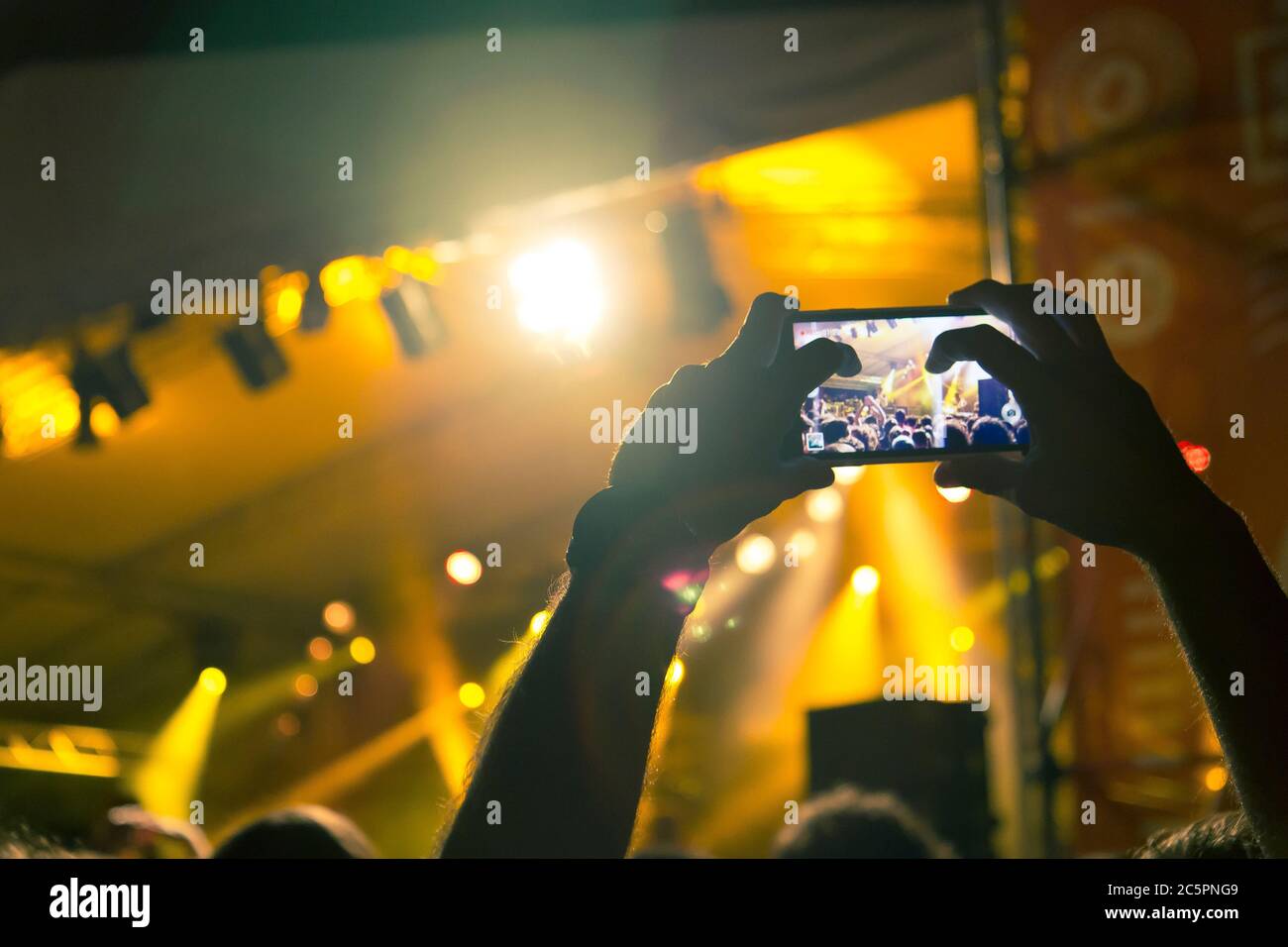 Concert crowd point of view in front of a lit stage for a night ...
