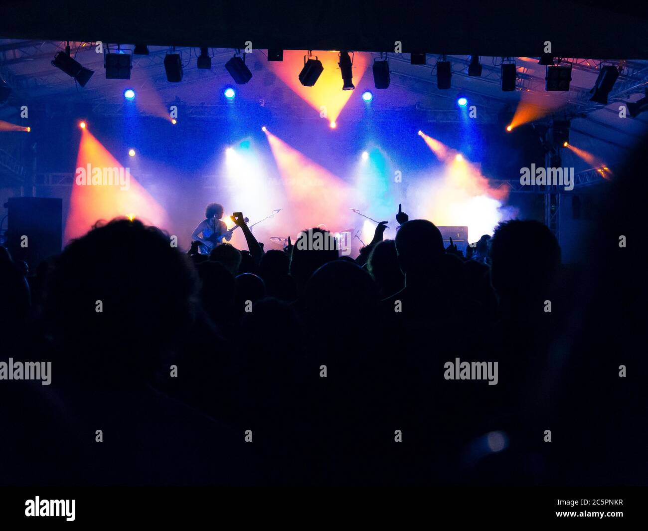 Concert crowd point of view in front of a lit stage for a night ...