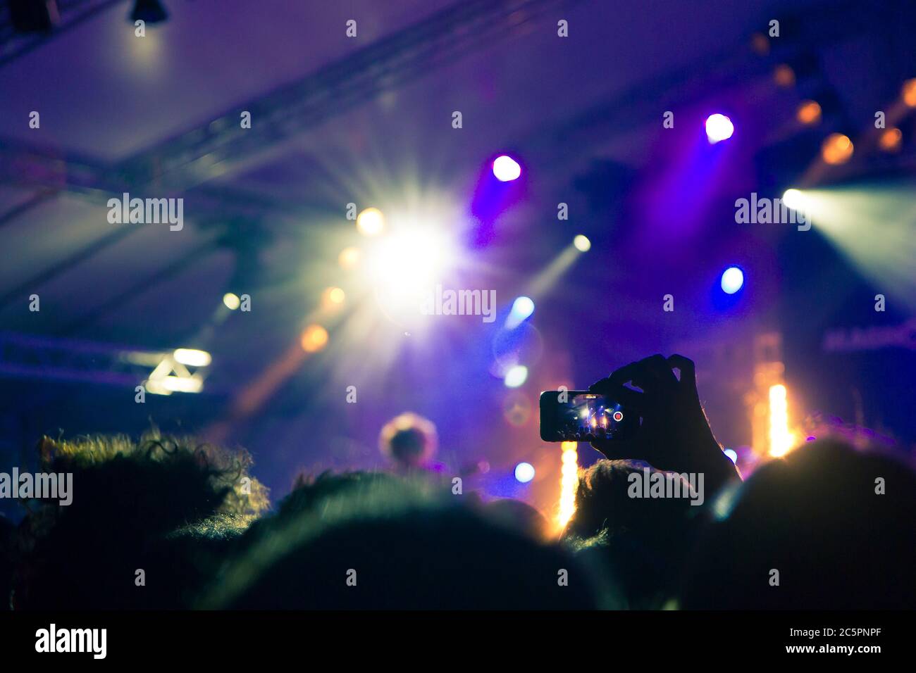 Concert crowd point of view in front of a lit stage for a night ...