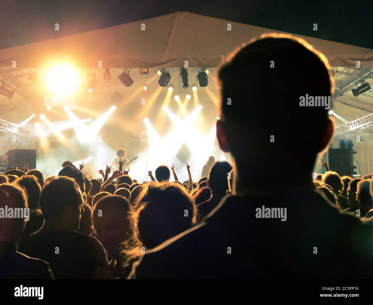 Concert crowd point of view in front of a lit stage for a night ...
