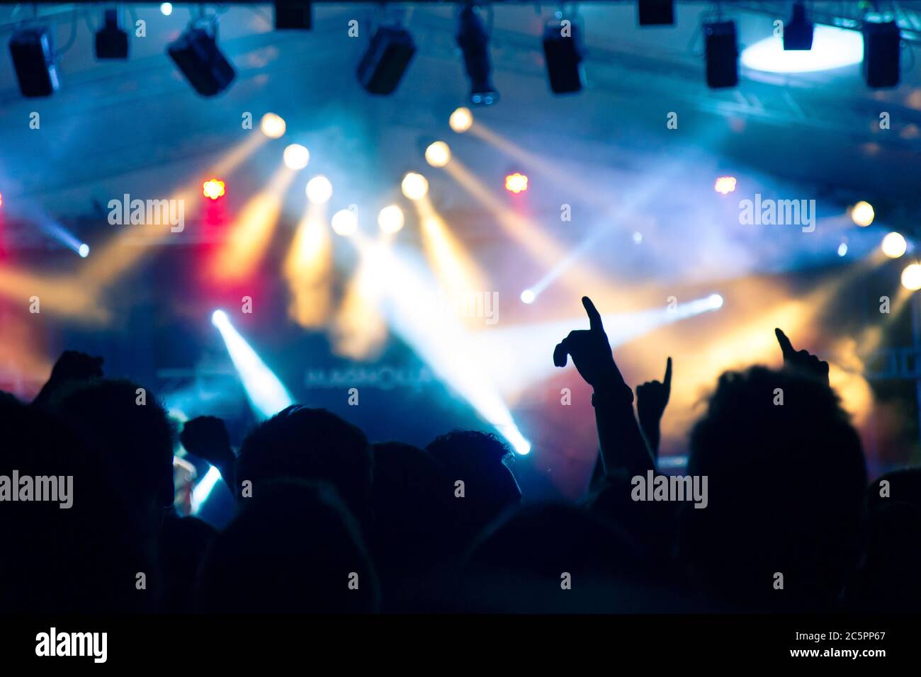 Concert crowd point of view in front of a lit stage for a night ...