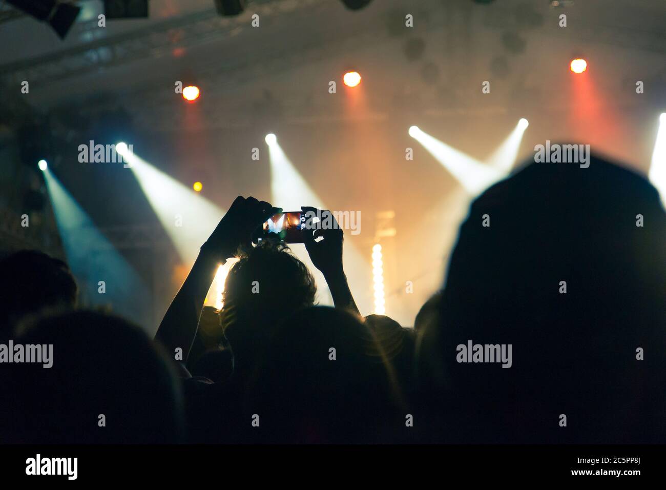 Concert crowd point of view in front of a lit stage for a night ...