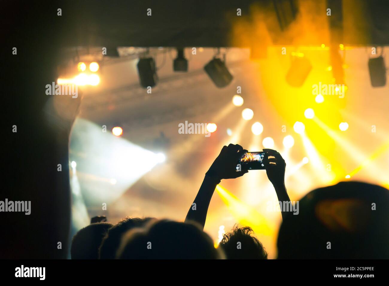 Concert crowd point of view in front of a lit stage for a night ...