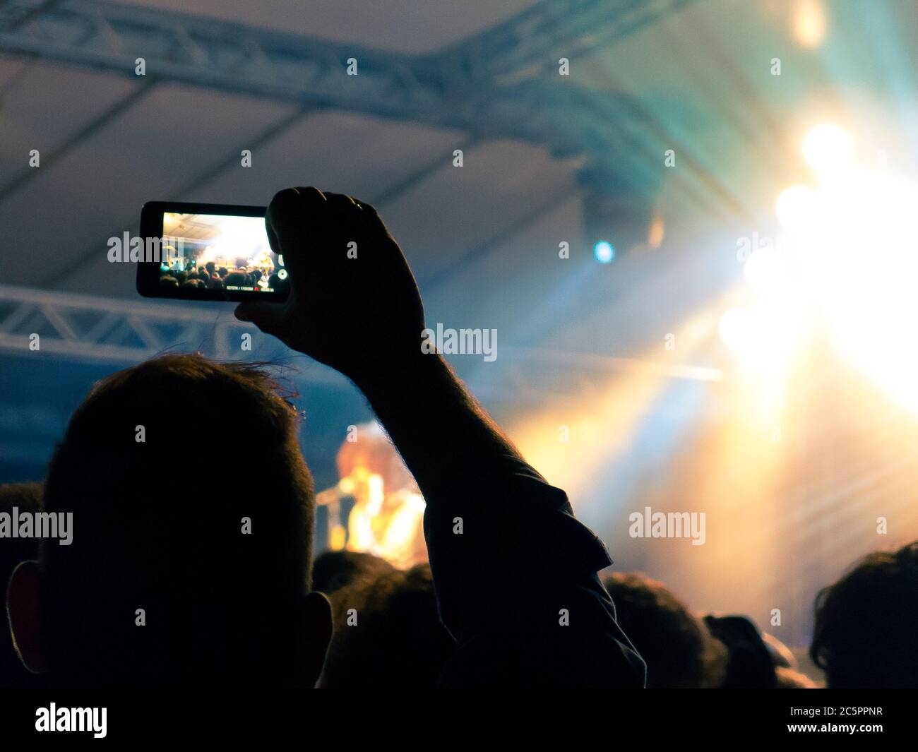 Concert crowd point of view in front of a lit stage for a night ...
