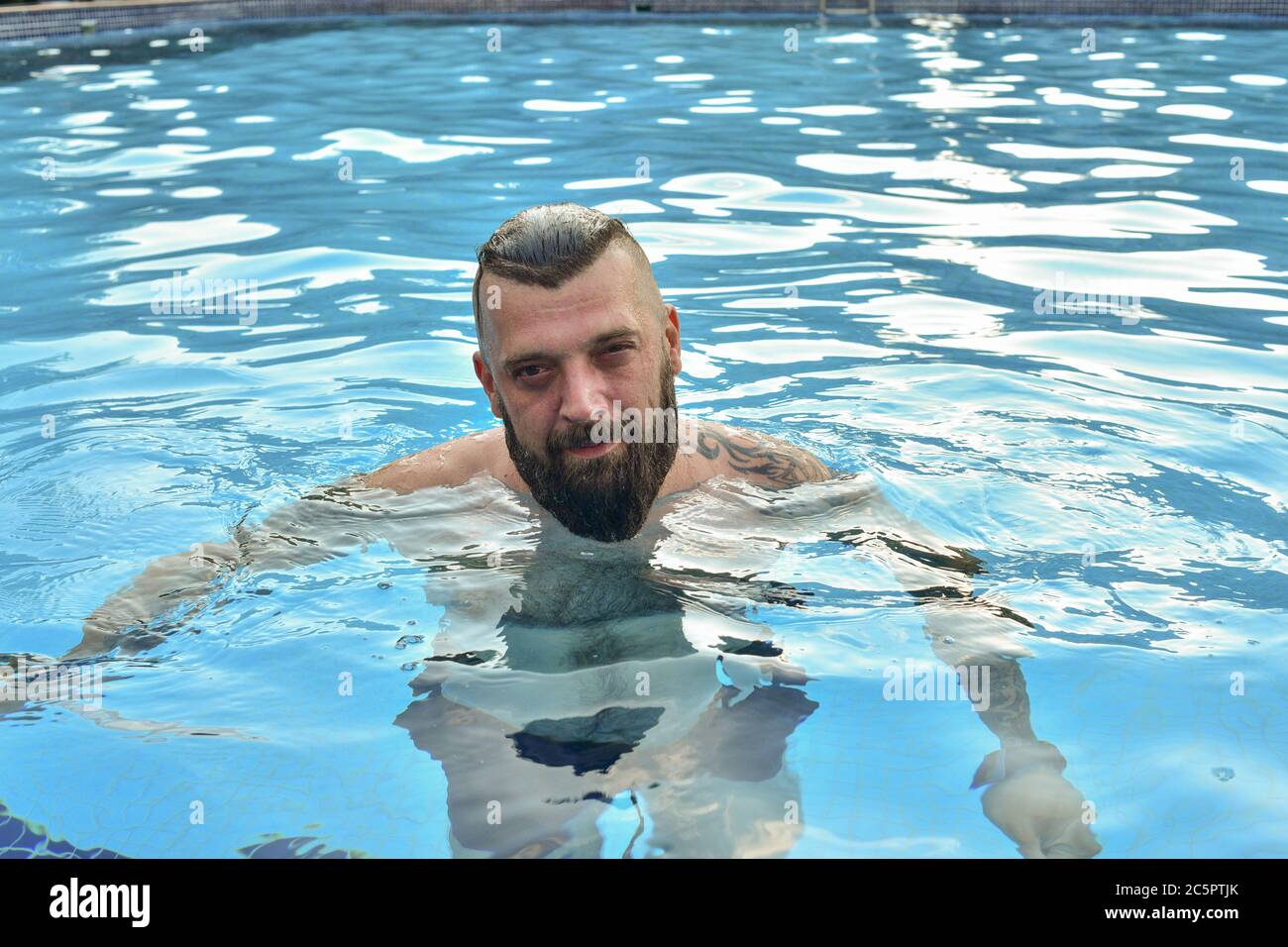 Bearded man swimming in a pool. Man with a beard in the pool. Brunette ...