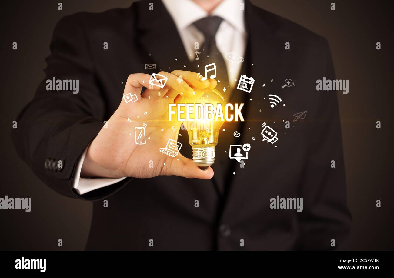 Businessman holding light bulb with FEEDBACK inscription, social media ...
