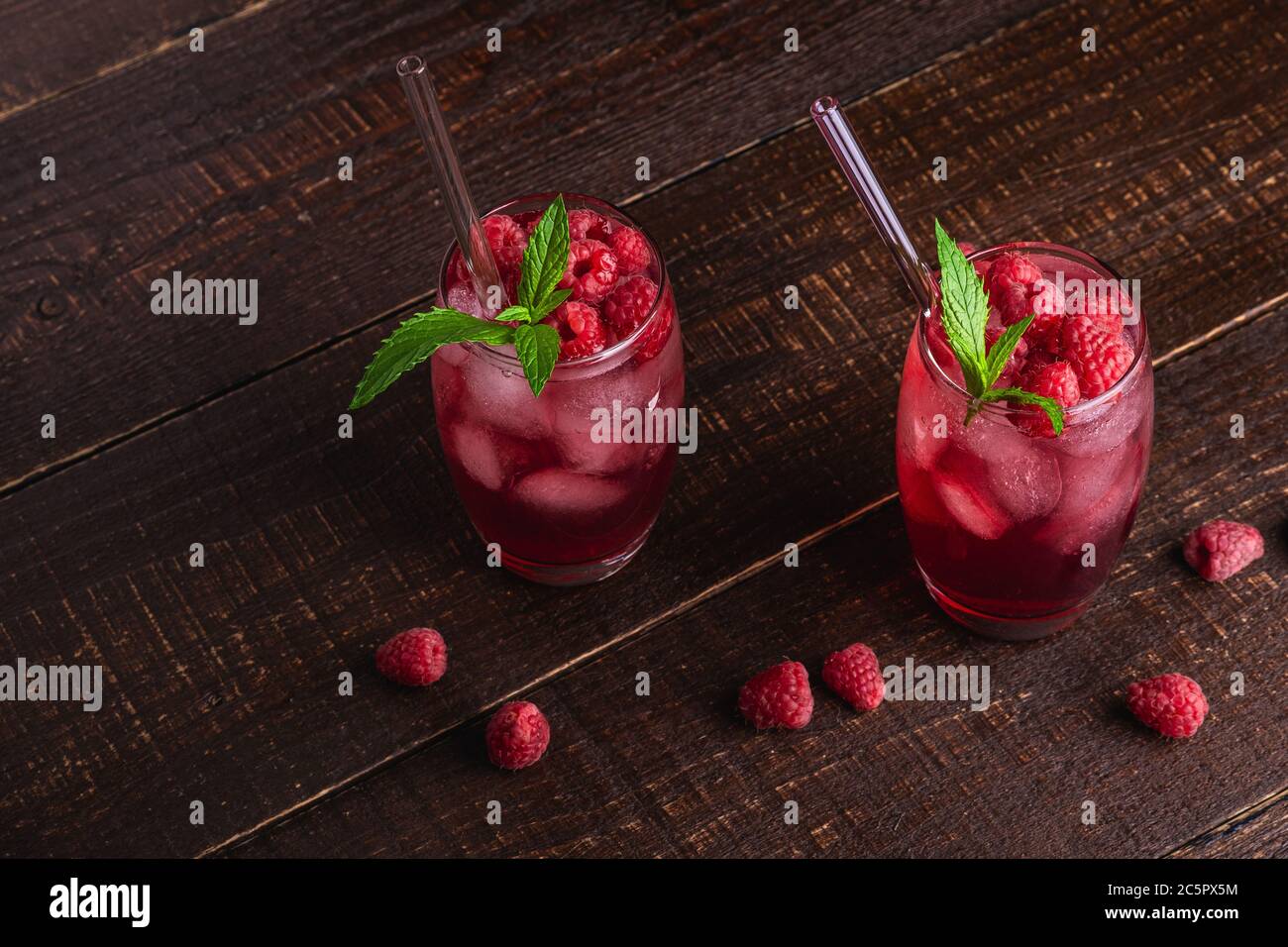Fresh ice cold berry juice drink with mint, summer raspberry lemonade two in glass with straws ...