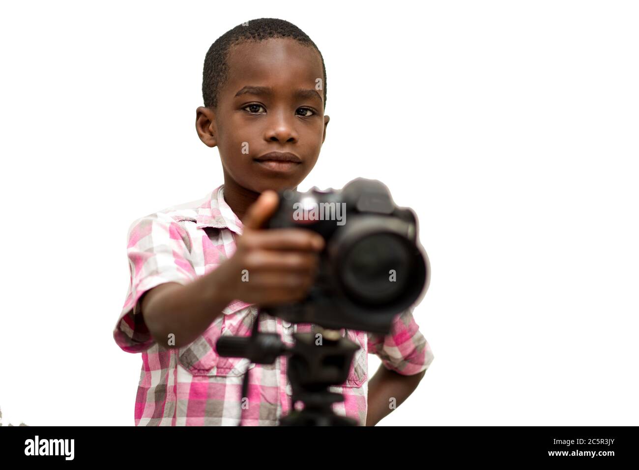 young boy standing with a camera on a tripod staring in front of him ...