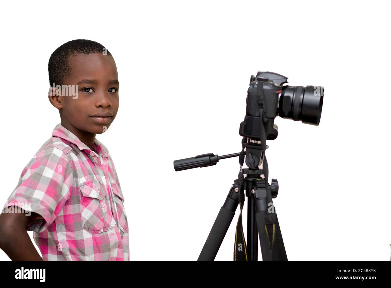 young boy standing behind camera resting on tripod putting his hands ...