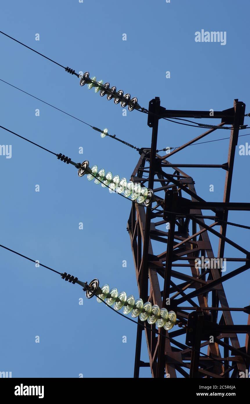 Electricity pylon with insulators and power lines. Blue sky background. Rusty weathered metal ...